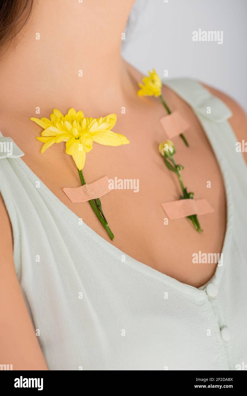 cropped view of plasters with yellow flowers on body of woman isolated ...