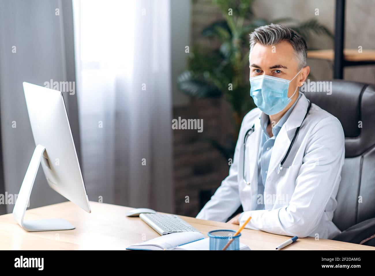 Portrait of male middle aged general doctor with gray hair dressed in ...