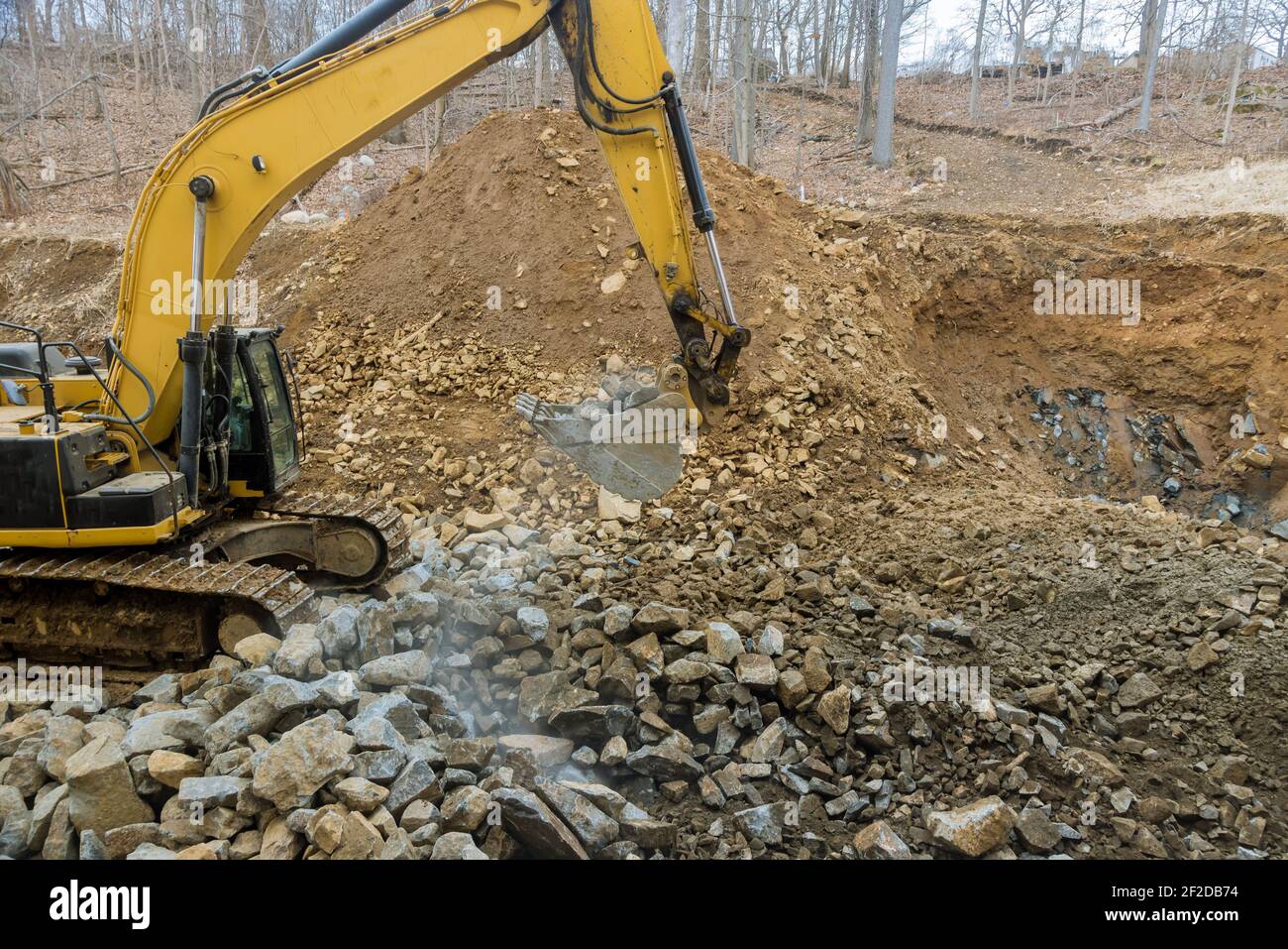 Excavator clearing rock and soil for new road construction site Stock ...