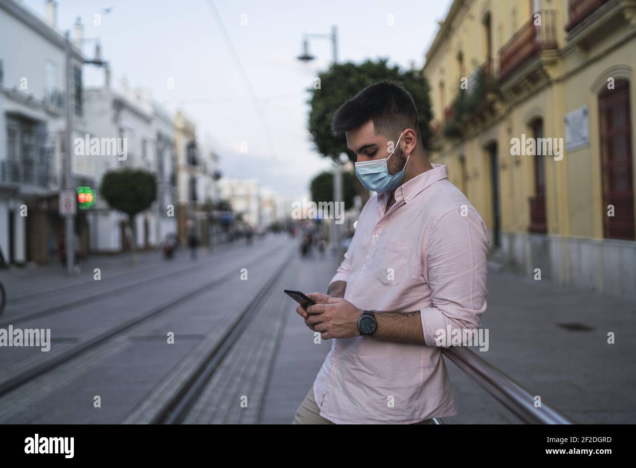 A handsome Spanish man wearing a mask and typing on his phone - new ...