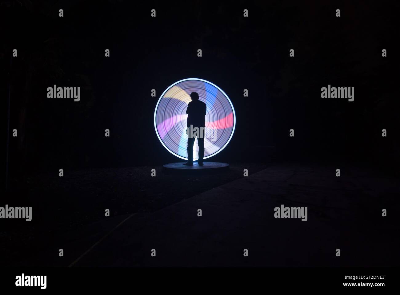 One person standing alone against beautiful color circle LED light ...