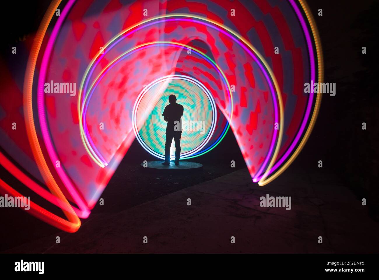 One person standing alone against beautiful color circle LED light ...