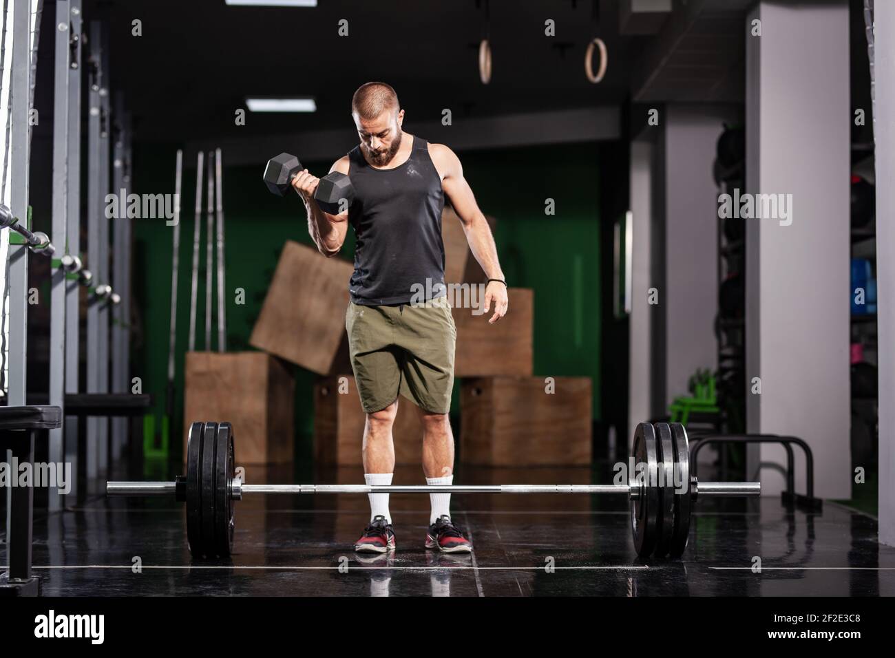 Muscular athlete lifting weights. Standing in front of heavy barbell ...