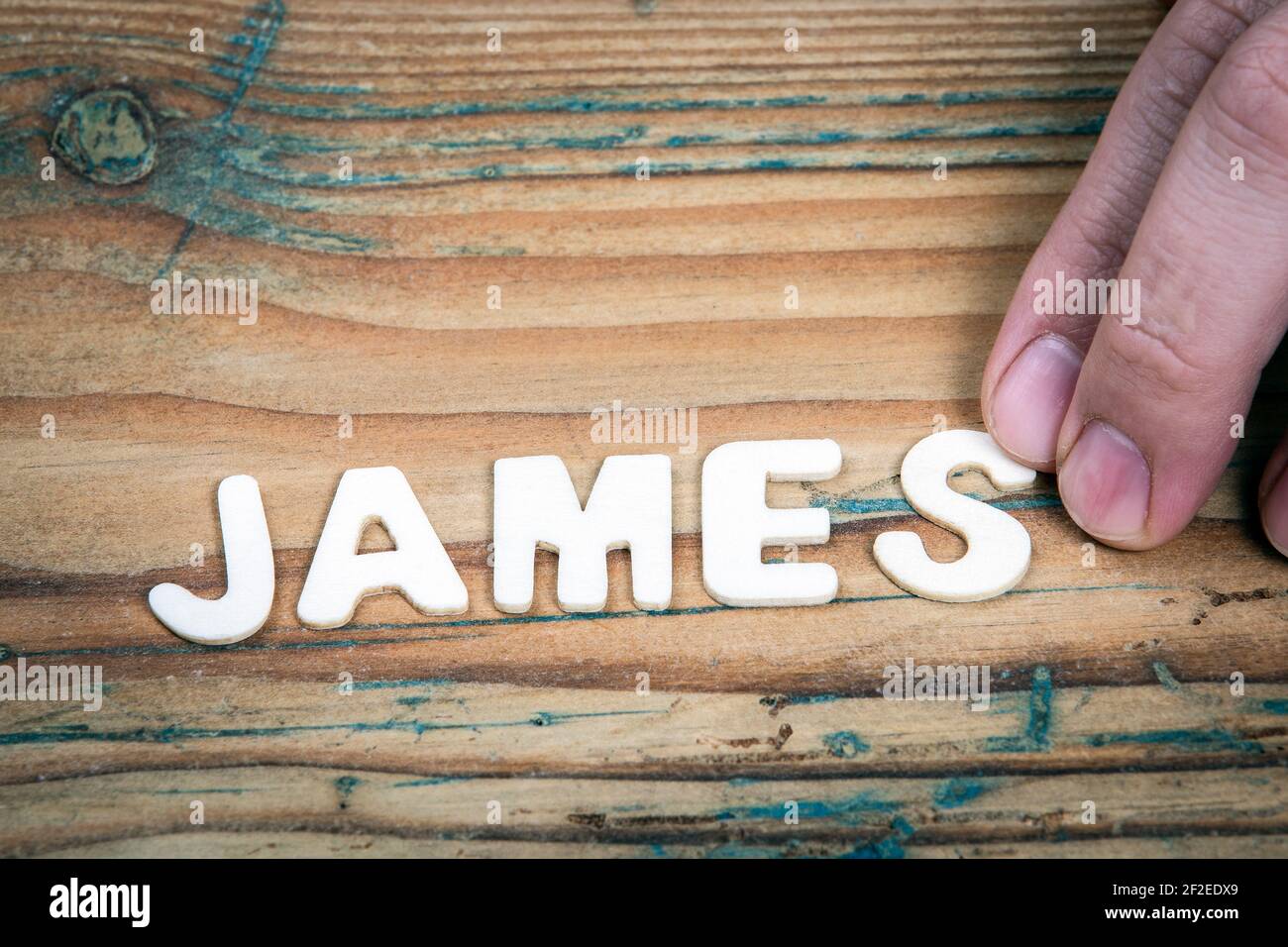 JAMES. Name of men and boys. White letters of the alphabet on a wooden ...