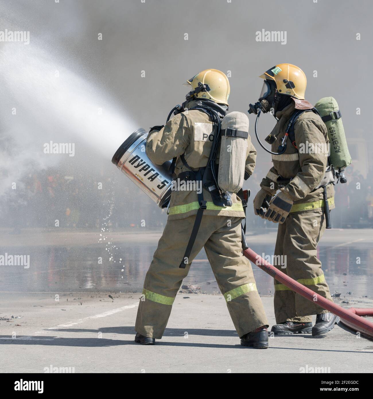 Two firefighters extinguishes fire from fire hose using firefighting ...