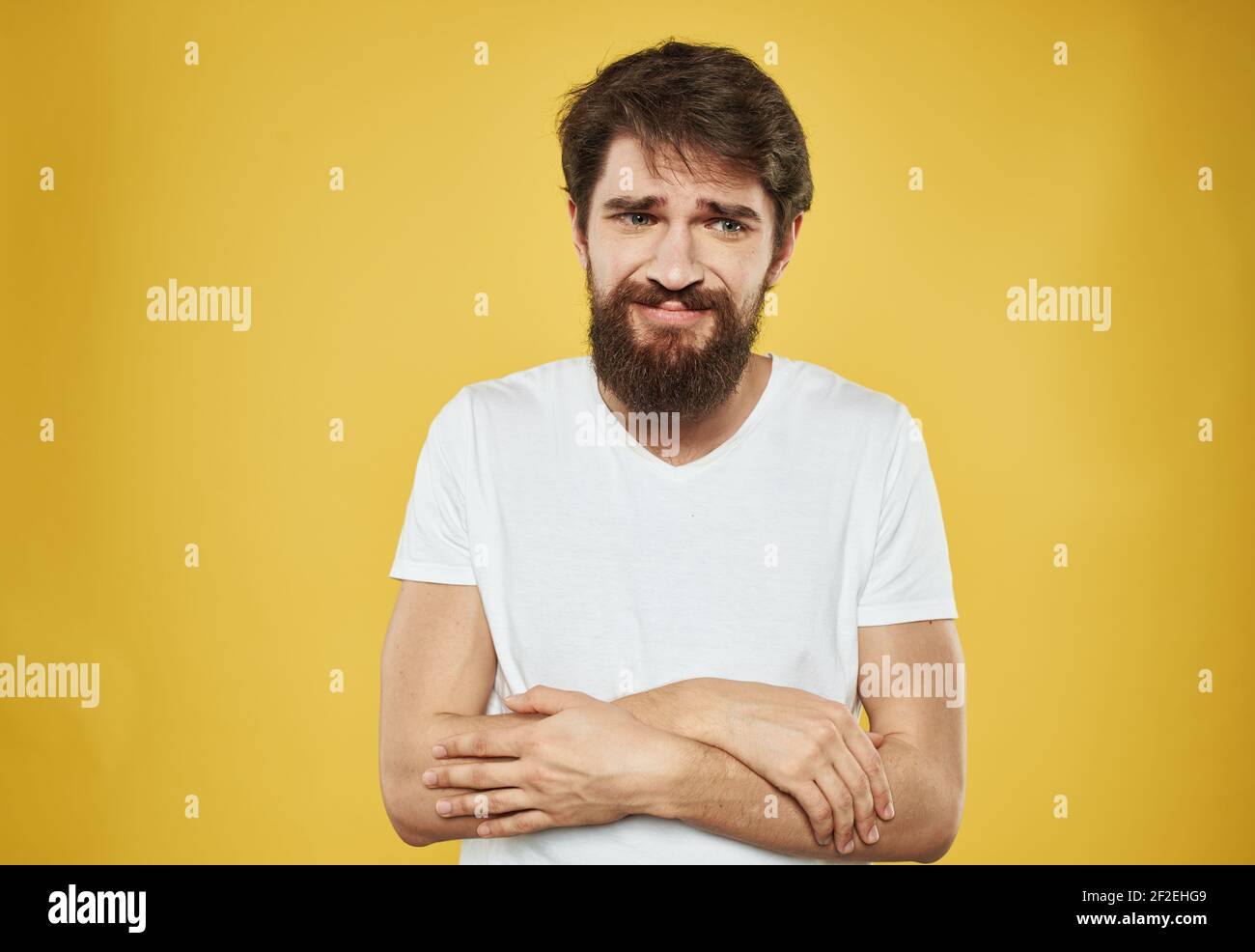 The man has his arms crossed over his chest against a yellow background ...