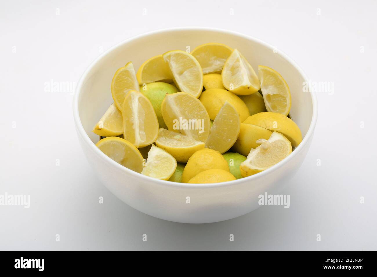 Lemon slices, arranged in a white bowl with white textured background ...