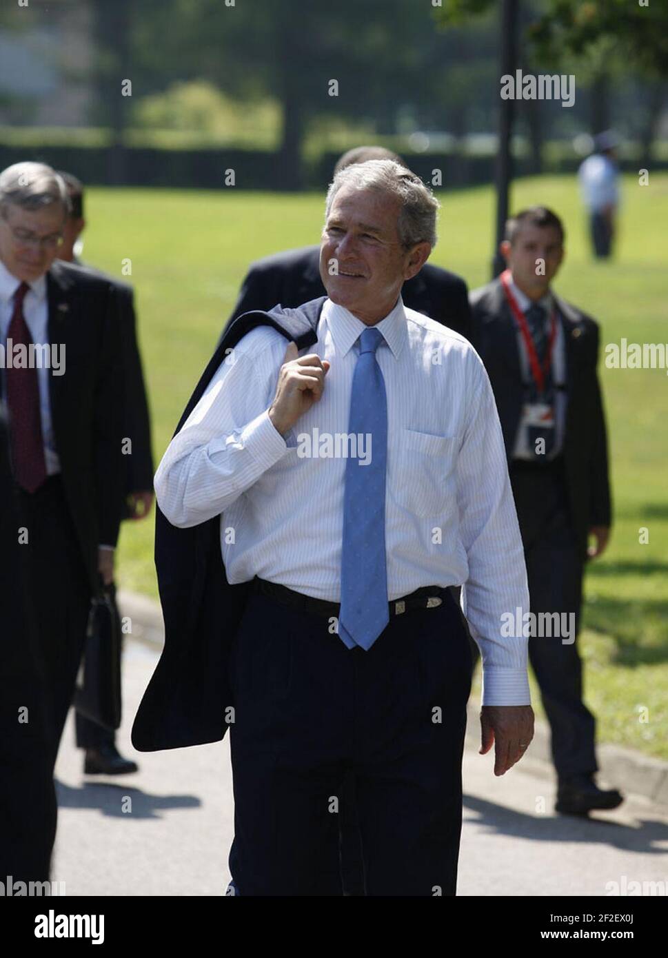 President George W. Bush walks carrying his jacket over his shoulder on ...