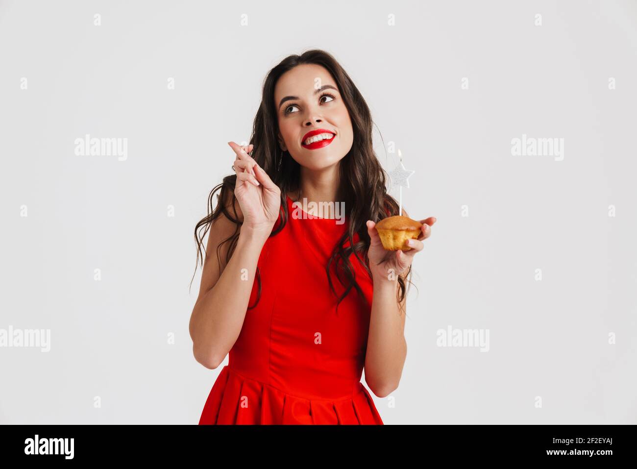 Happy brunette girl dancing holding fingers crossed while posing with ...