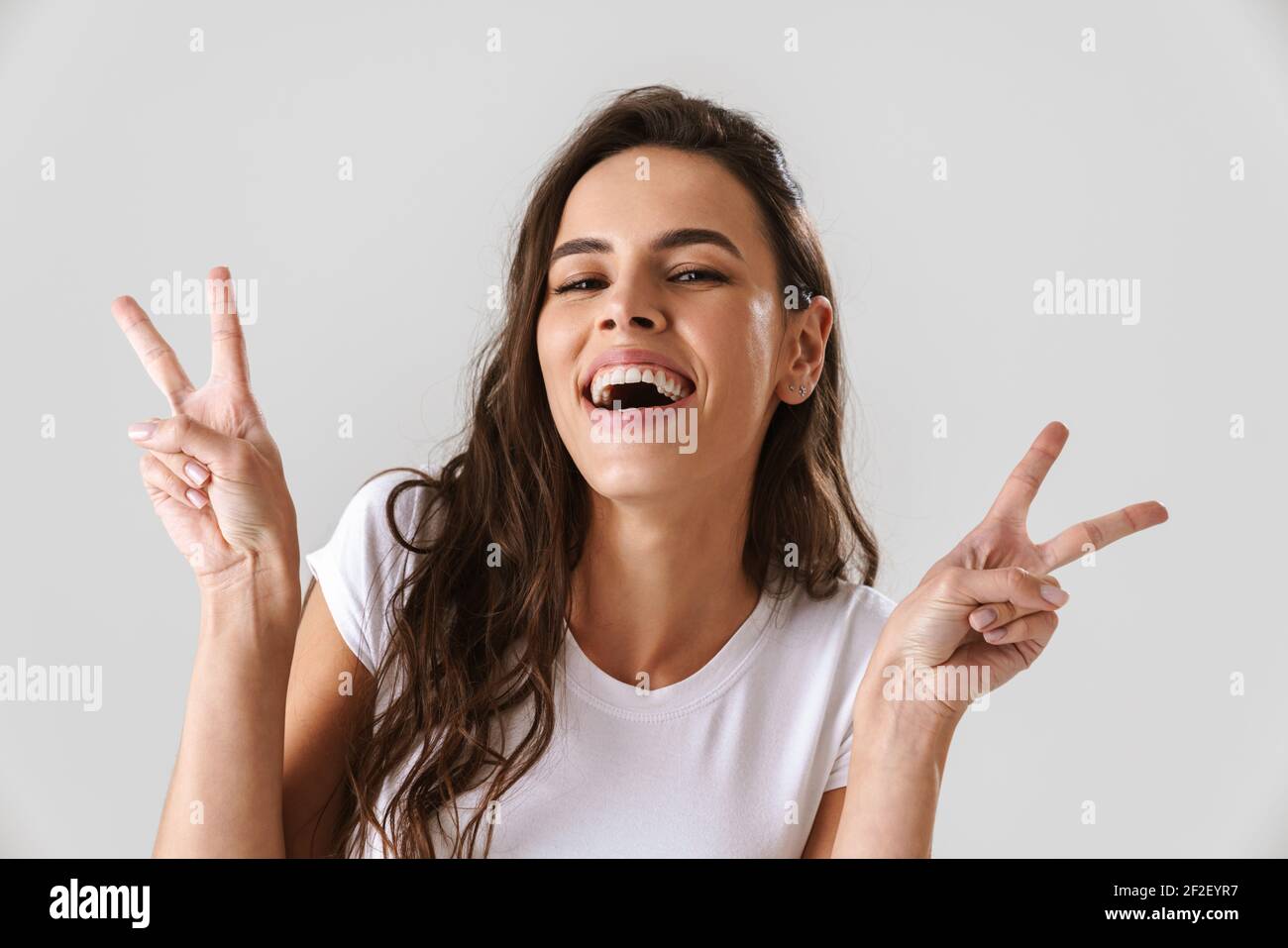 Cheerful beautiful nice girl smiling and showing peace sign isolated ...