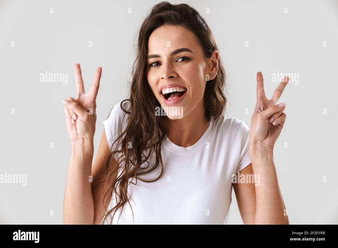 Cheerful beautiful nice girl smiling and showing peace sign isolated ...
