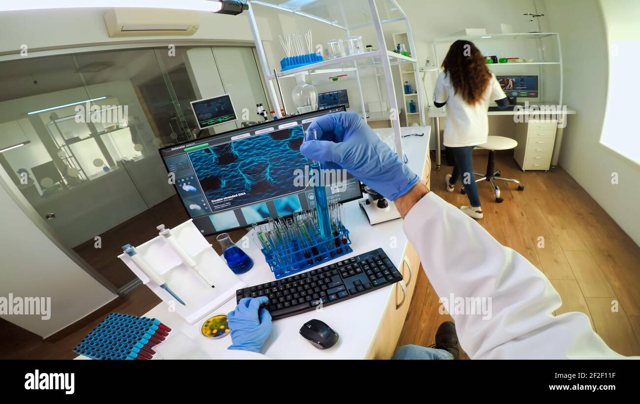 Laboratory doctor holding test tube with blue sample, writing on ...