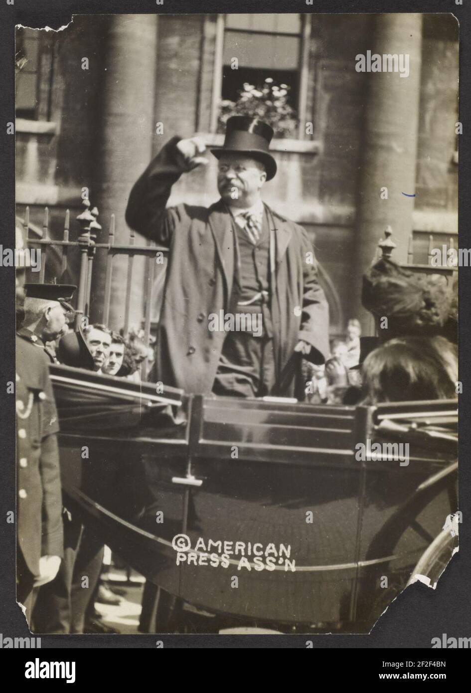 President Theodore Roosevelt standing in an open carriage looking out ...