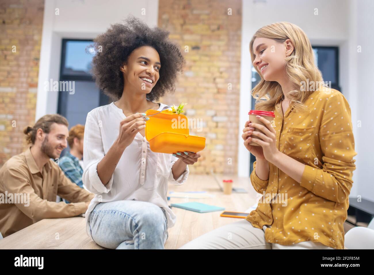 Curly-haired mulatta eating lunch with her office colleague Stock Photo ...