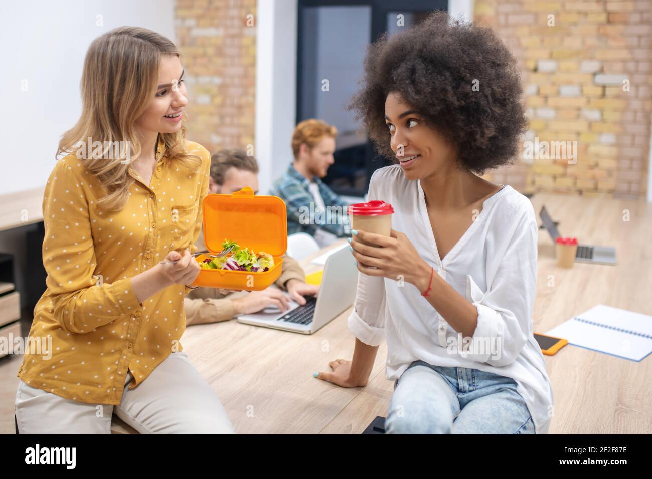 Two female colleagues eating lunch together and talking Stock Photo - Alamy