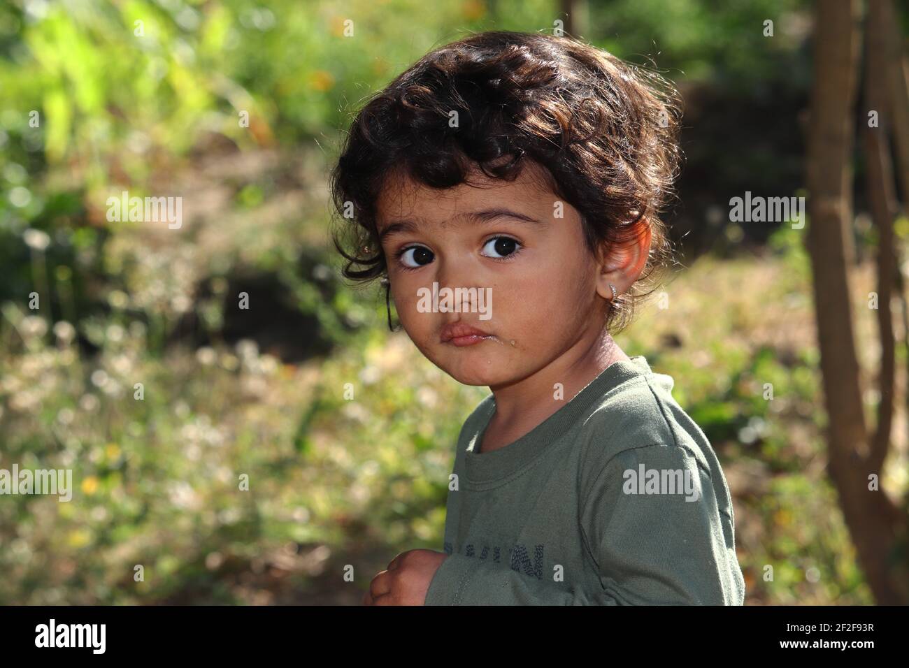 closeup A small Indian child looking obliquely in the garden, india ...