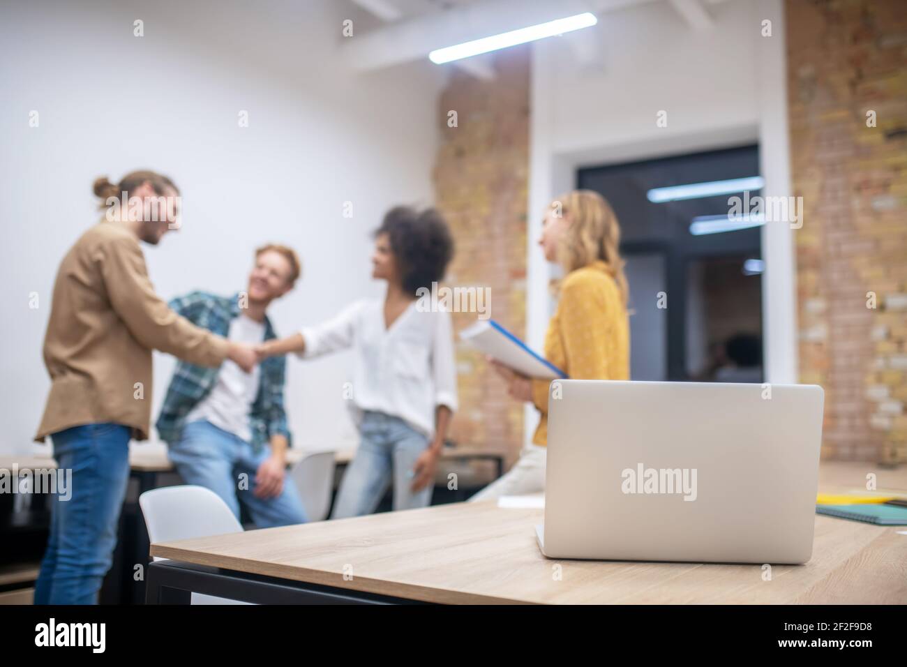 Group of young professionals meeting a new colleague and looking ...