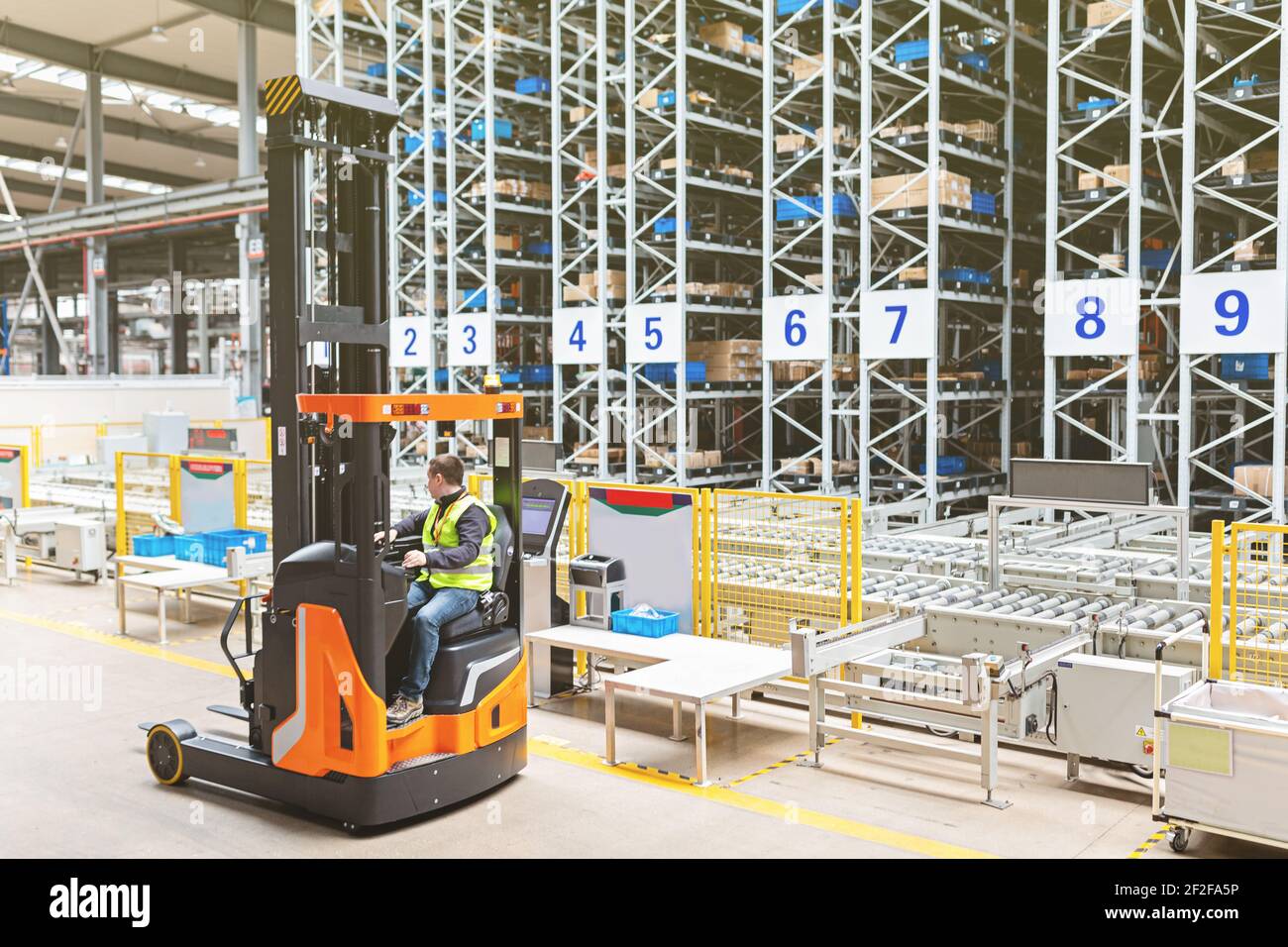 Storehouse employee in uniform working on forklift in modern automatic ...