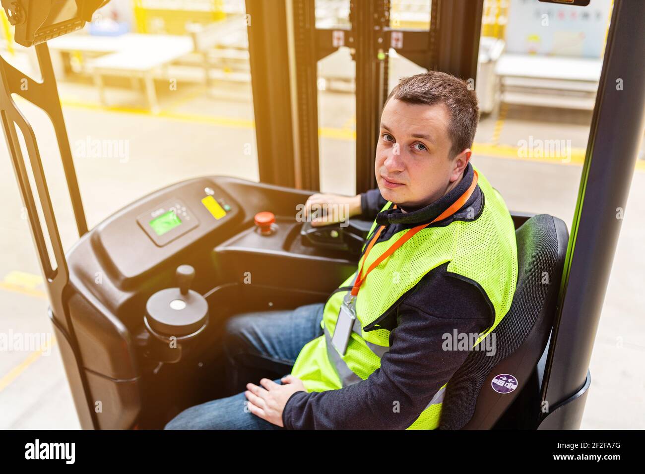 Storehouse employee in uniform working on forklift in modern automatic ...