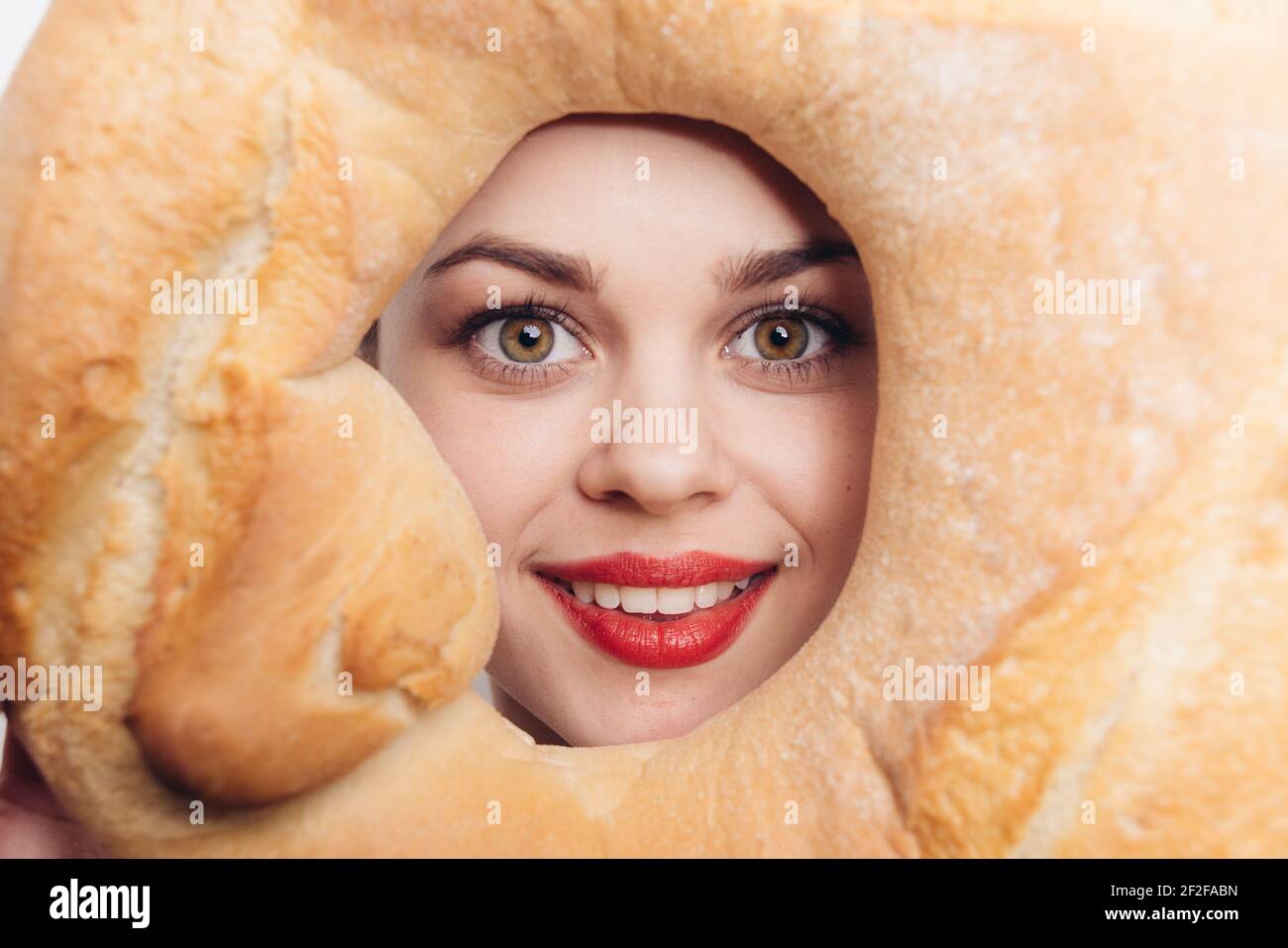 happy woman with round loaf of bread in front of face bright makeup ...