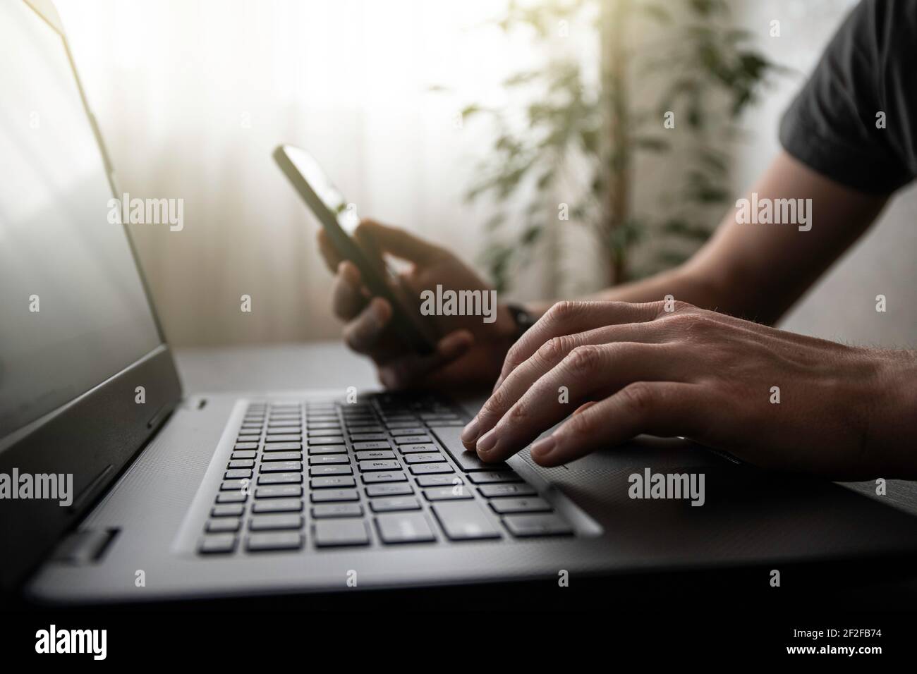 Man use smartphone and laptop in office or at home. Side view shot of ...