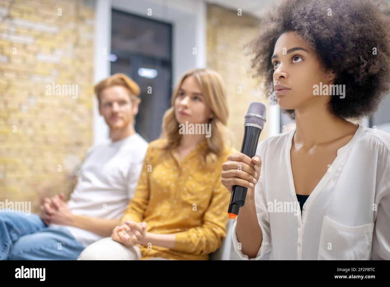 Cute mulatts with a microphone talking to the audience Stock Photo - Alamy