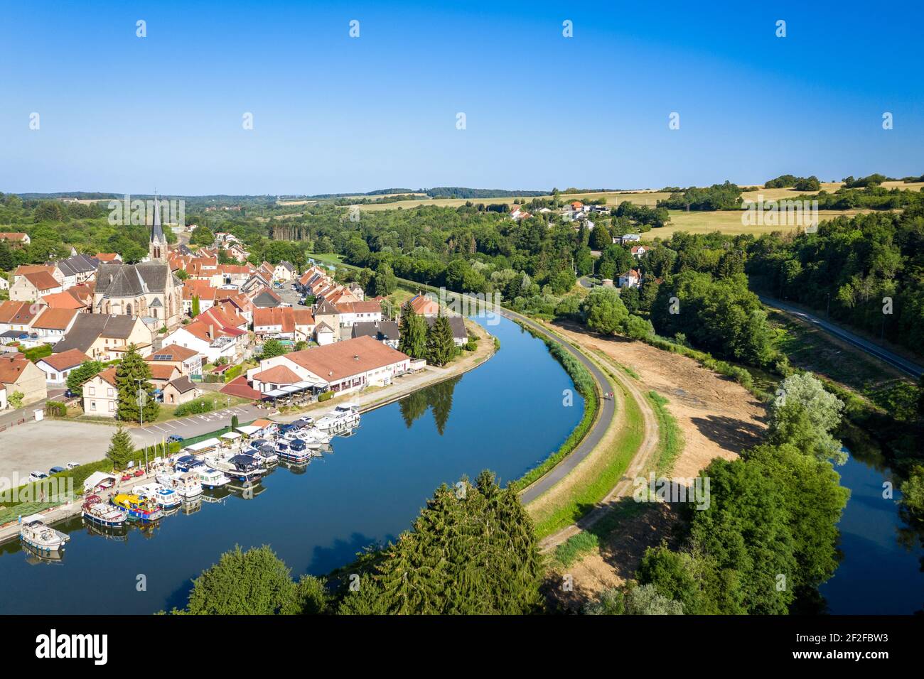 Aerial view on bicycle path leading along river. Boats in port and town ...