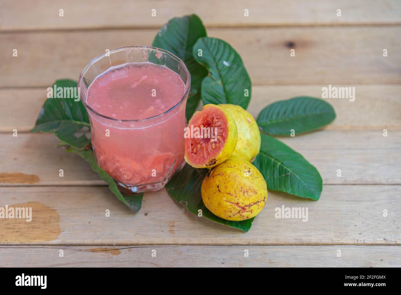 Glass of guava juice. Detox juice. Natural and refreshing drink. Guavas on wooden background ...