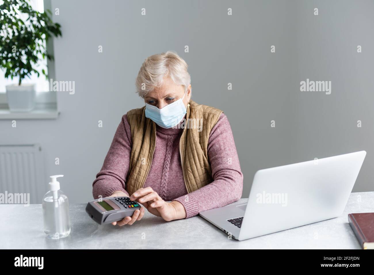 elderly woman sitting with laptop and bank terminal Stock Photo - Alamy