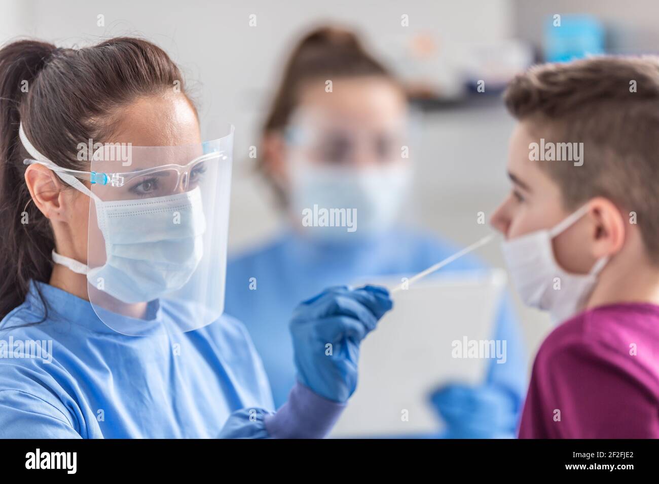 Medical staff uses swab for taking nose sample from a young boy to test ...