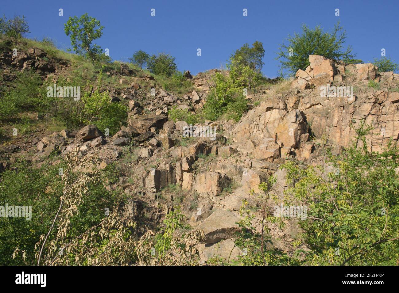 A rocky slope of an abandoned granite quarry in the Nikolaev region of ...