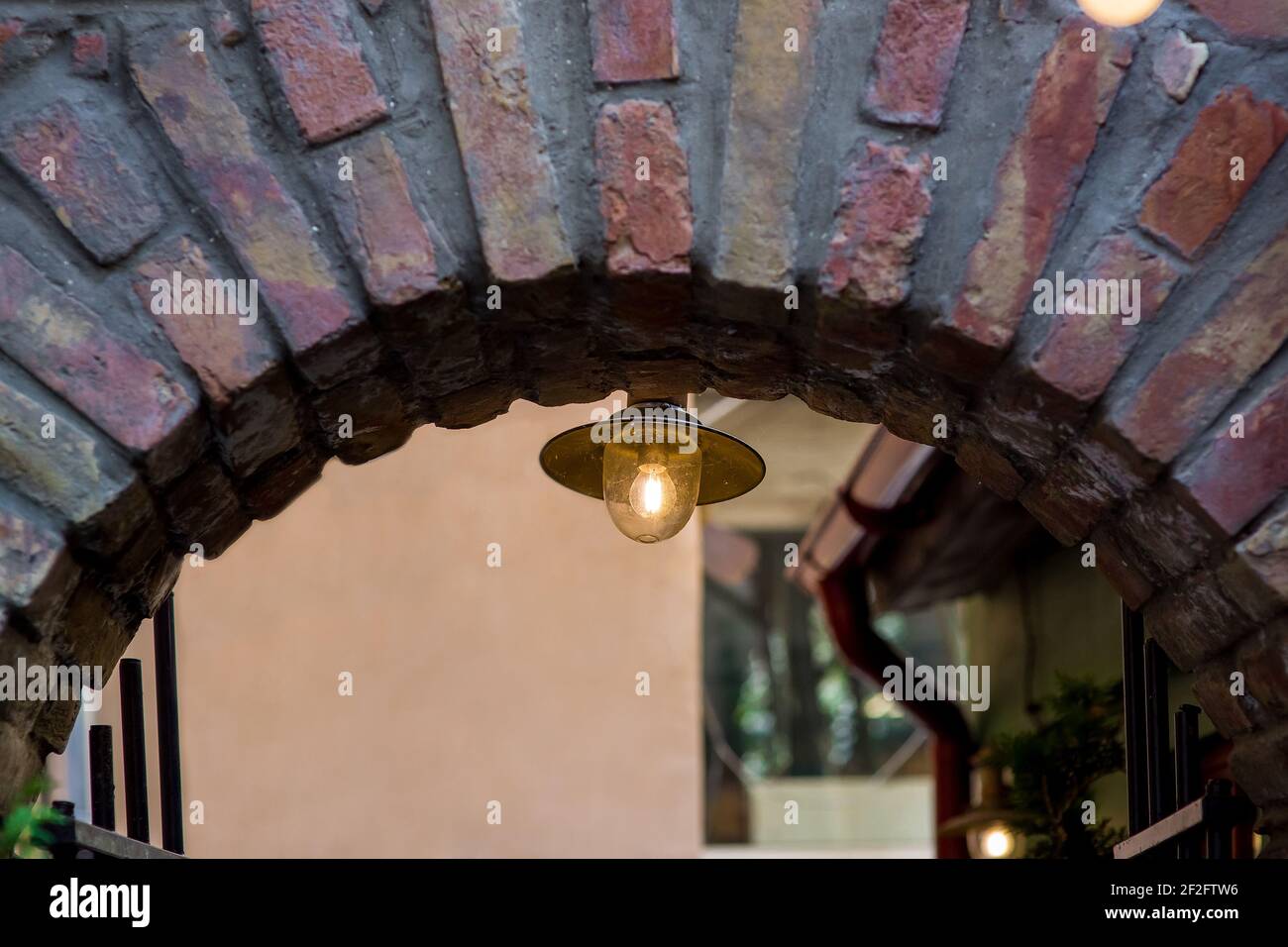 retro street lamp glows with warm light on the brick arch of the old ...