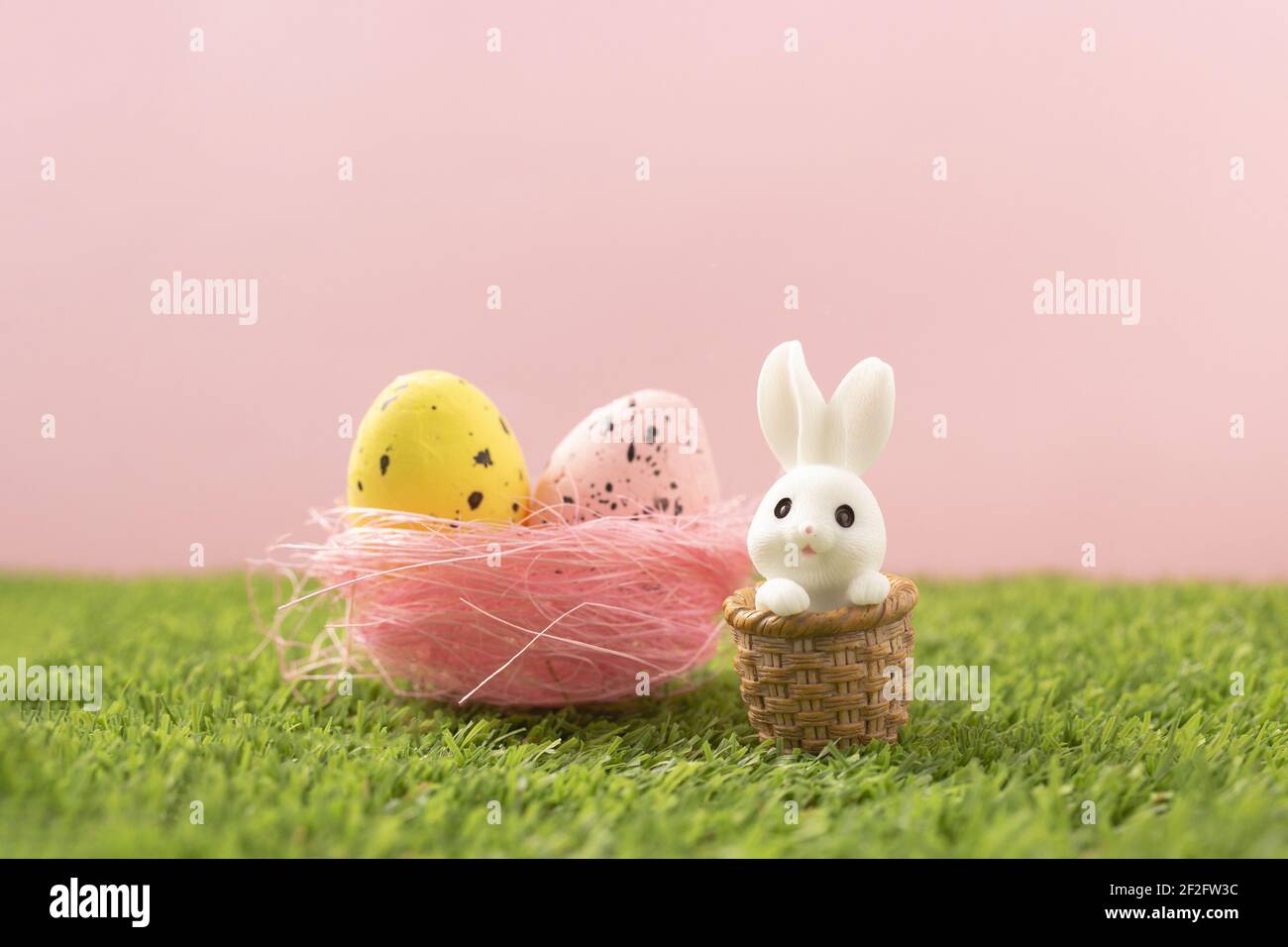 A soft focus of speckled Easter eggs in a pink nest and a cute rabbit ...