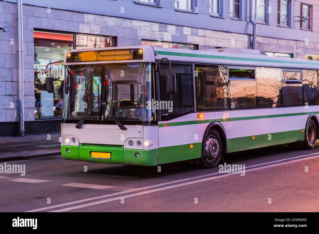 Passenger bus moves straight along city street Stock Photo - Alamy