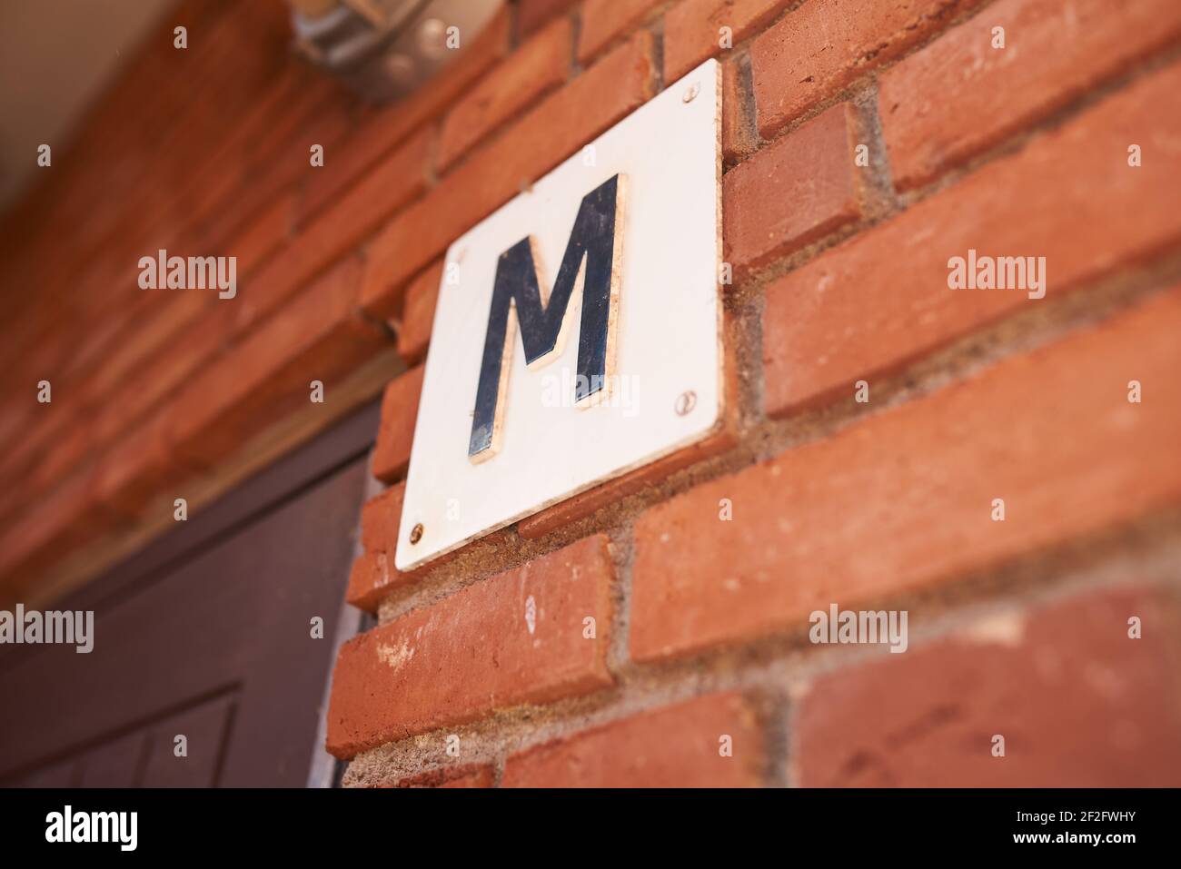 The letter M on a sign on a red building Stock Photo - Alamy