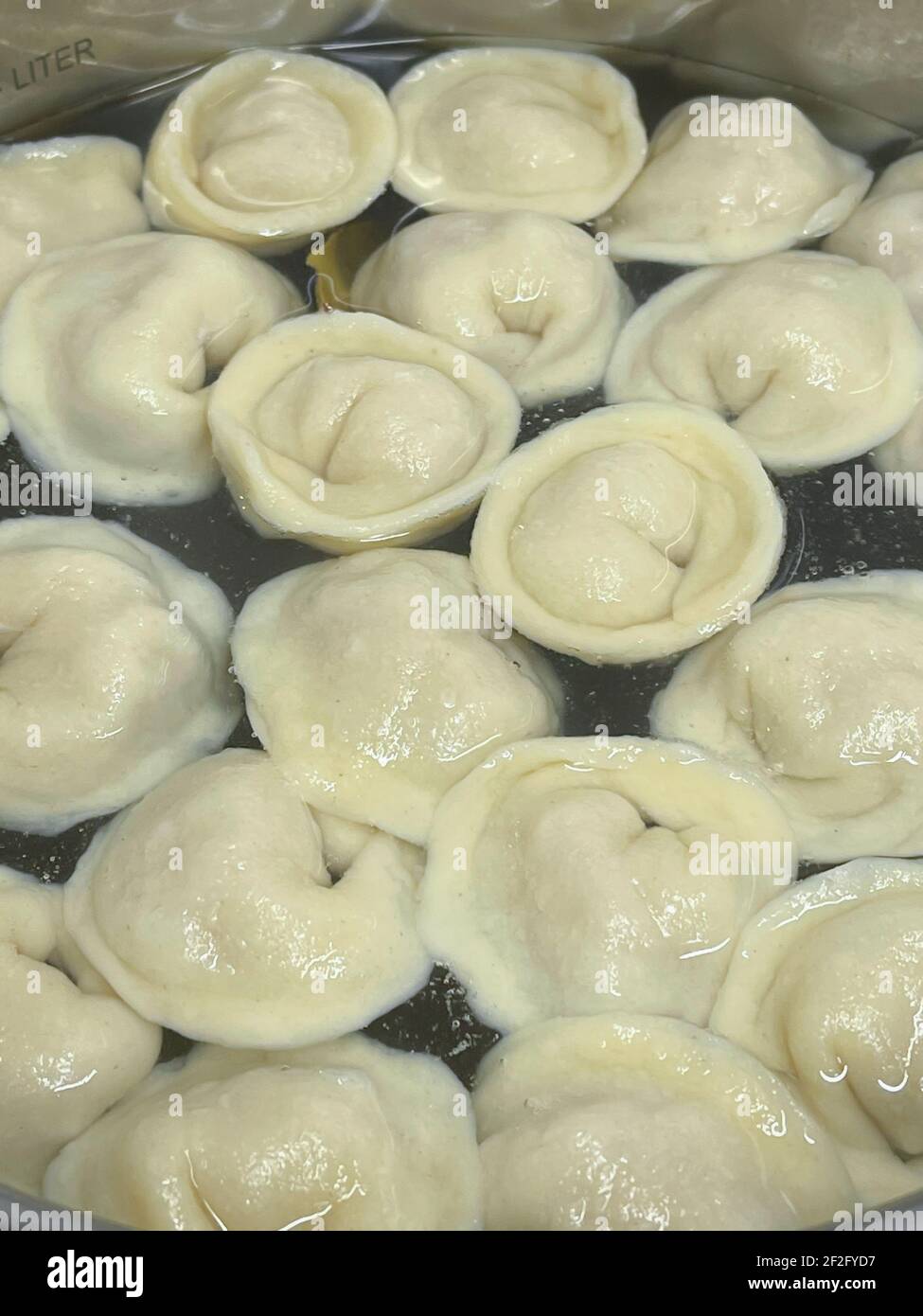 Cooking dumplings by boiling in water in a pan at kitchen. Close-up ...