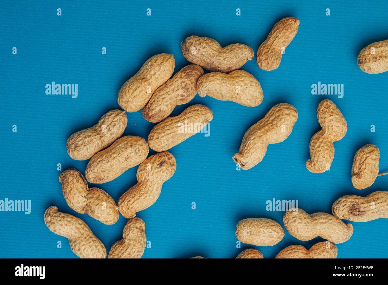 peanuts in shells on a blue background snack rest Stock Photo - Alamy