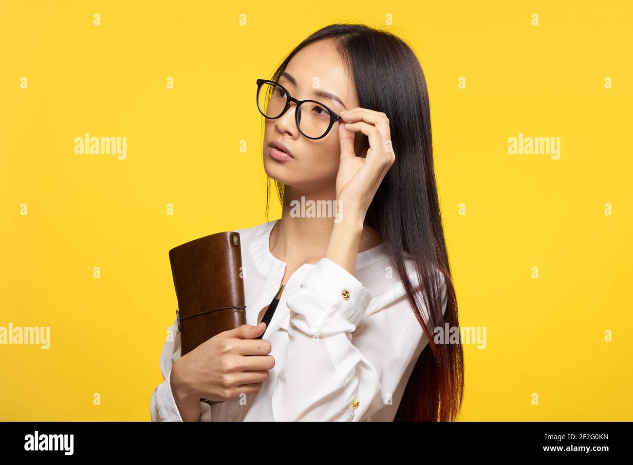 elegant woman holding notepad glasses manager executive yellow background Stock Photo - Alamy