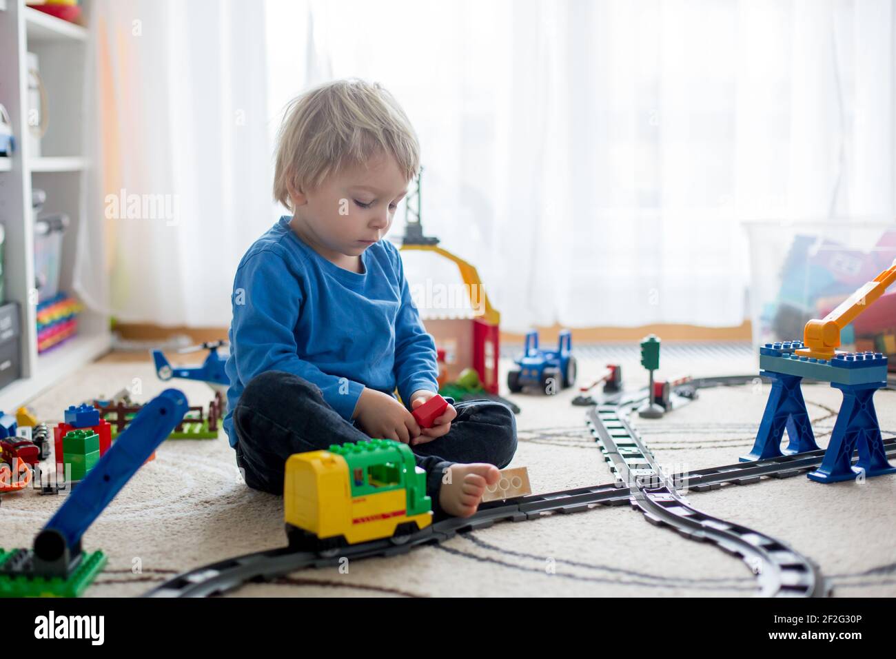 Adorable little boy playing with colorful plastic construction blocks ...