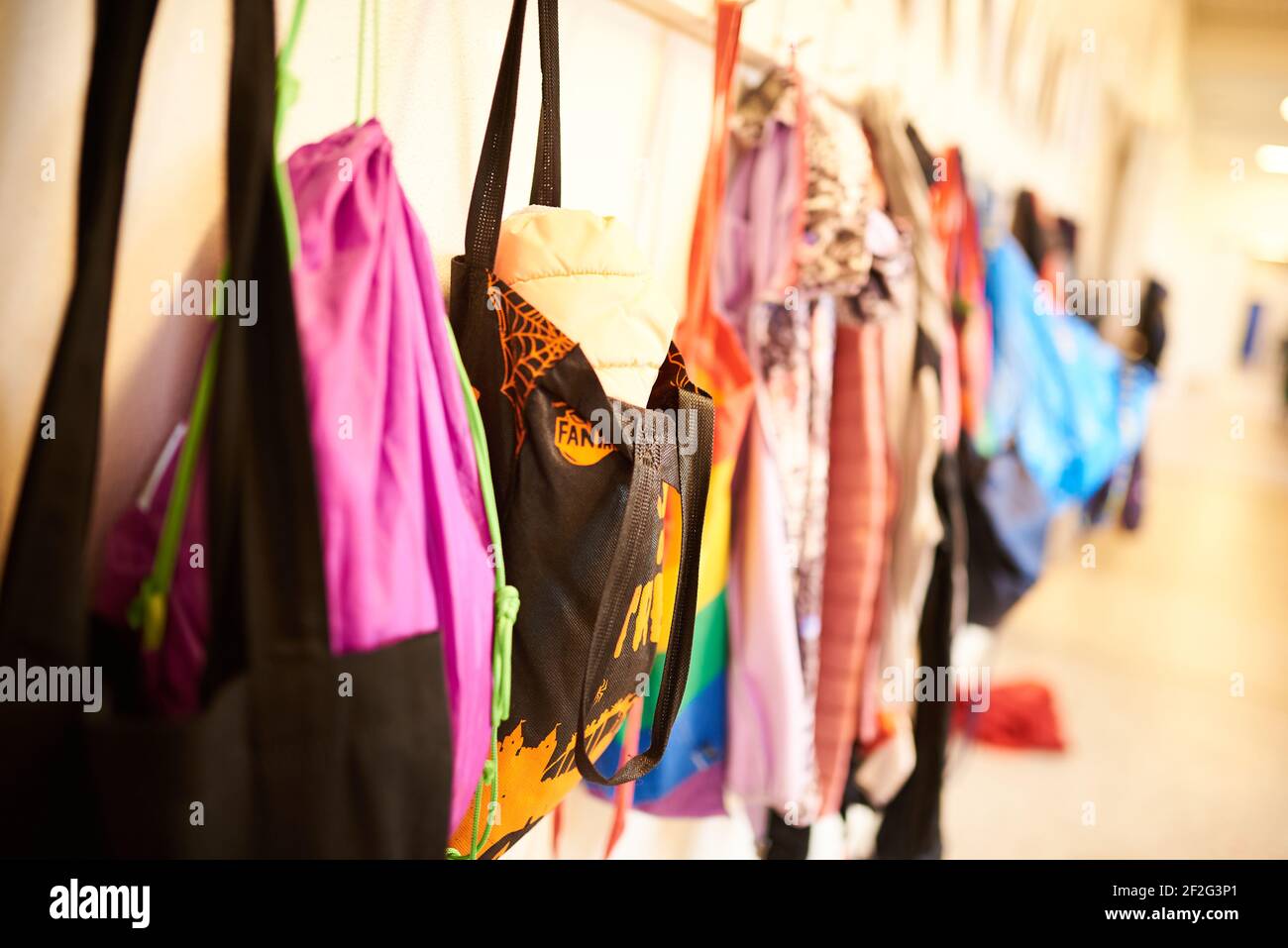 Small school backpacks hanging on a rack Stock Photo - Alamy