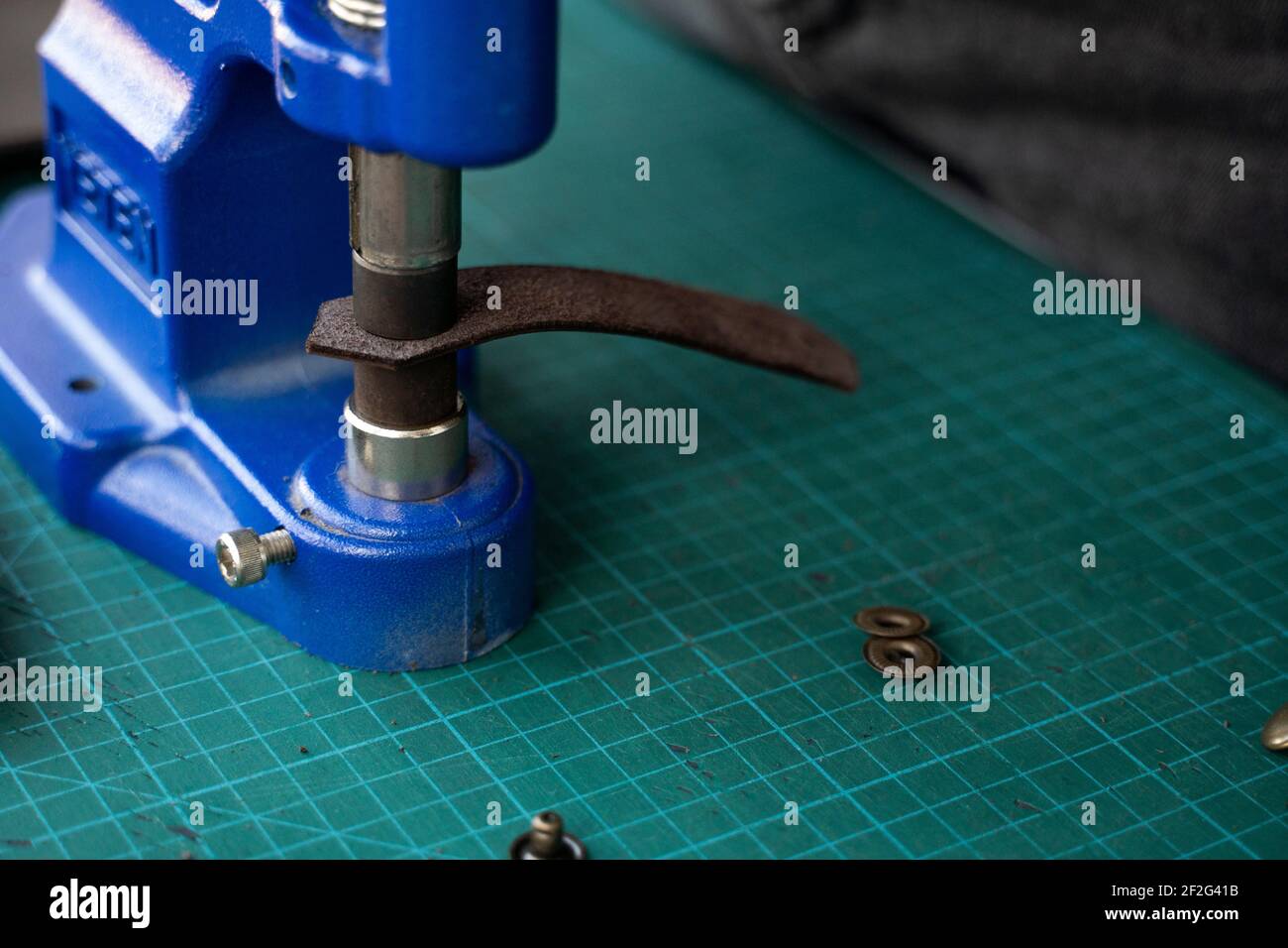 Artisan using hand press for setting snaps in leather for makes a ...