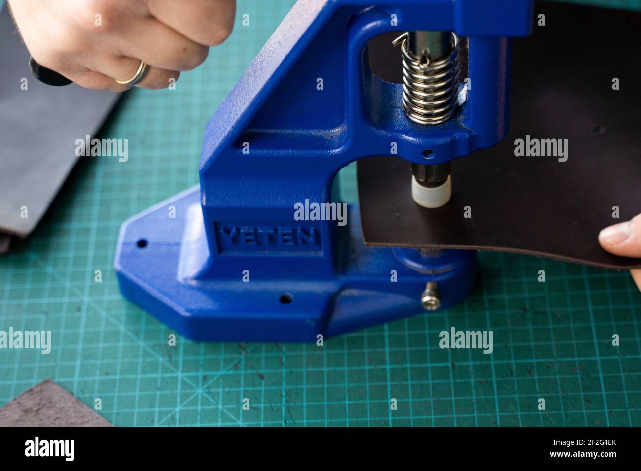 Artisan using hand press for setting snaps in leather for makes a ...