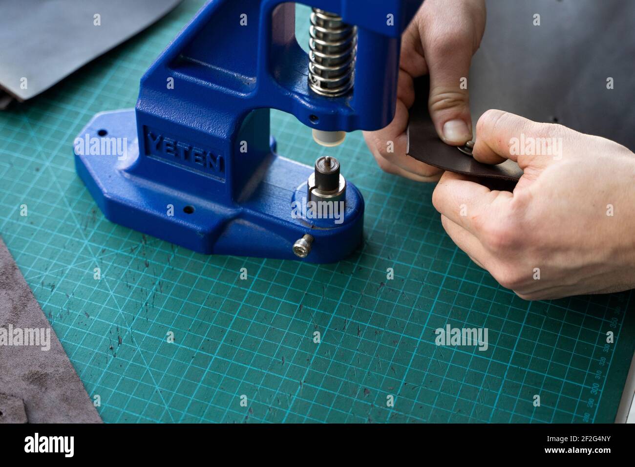 Artisan using hand press for setting snaps in leather for makes a ...