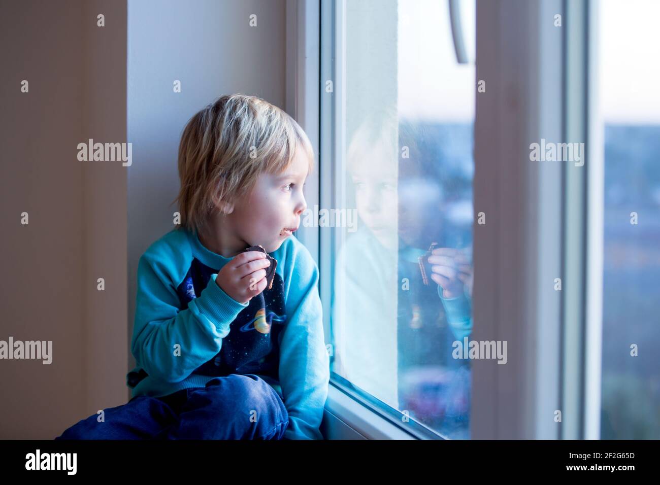 toddler child, sitting on the window on sunset, looking out Stock Photo ...