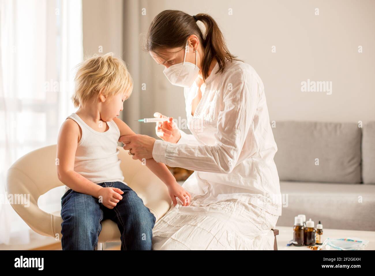 Little toddler child, blond boy, getting injection in consulting room ...