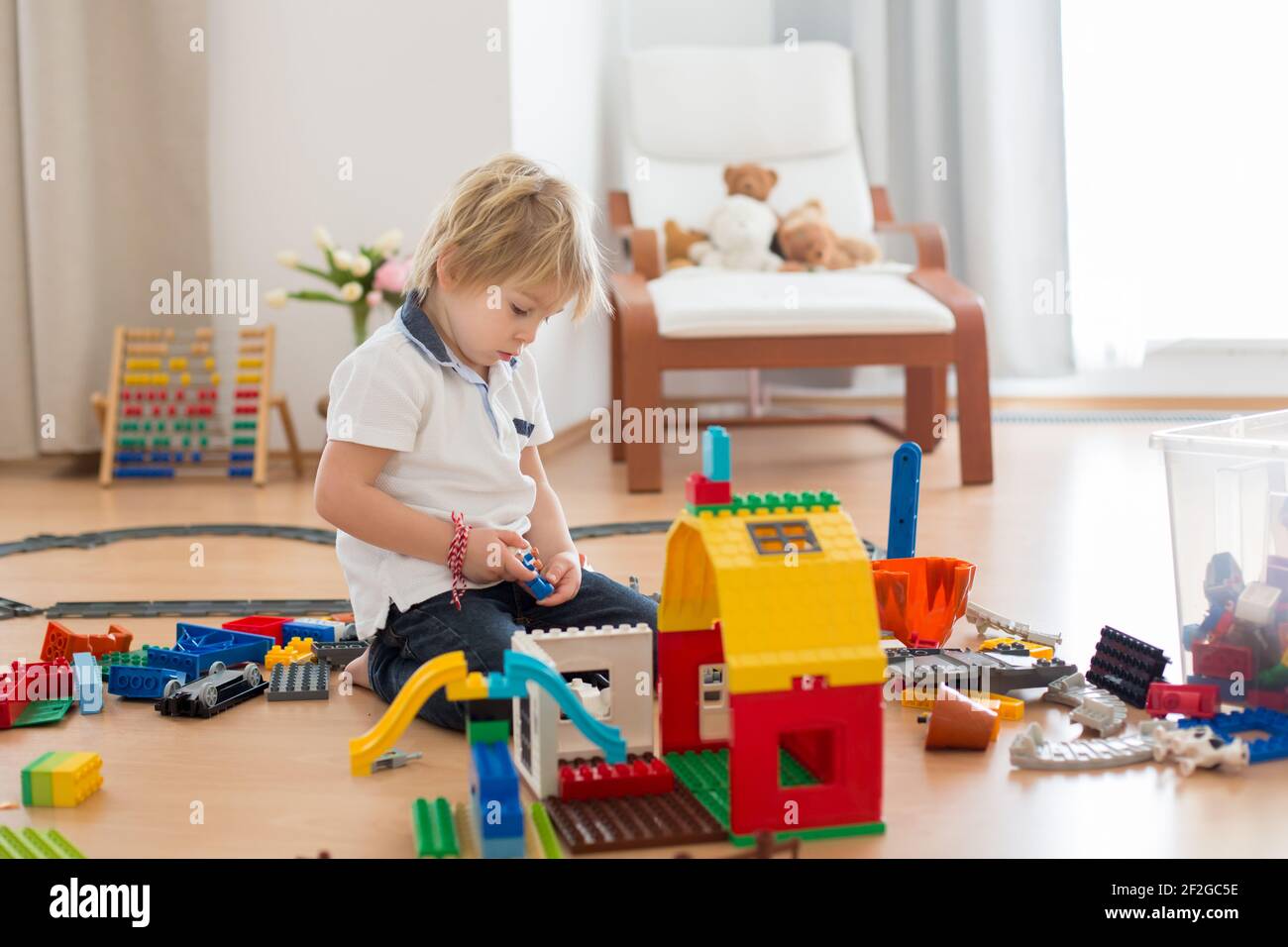 Cute child, playing with colorful toy blocks. Little boy building house ...