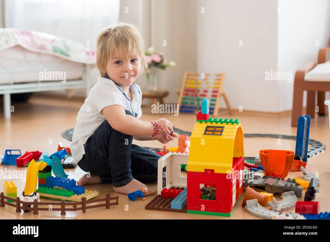 Cute child, playing with colorful toy blocks. Little boy building house ...