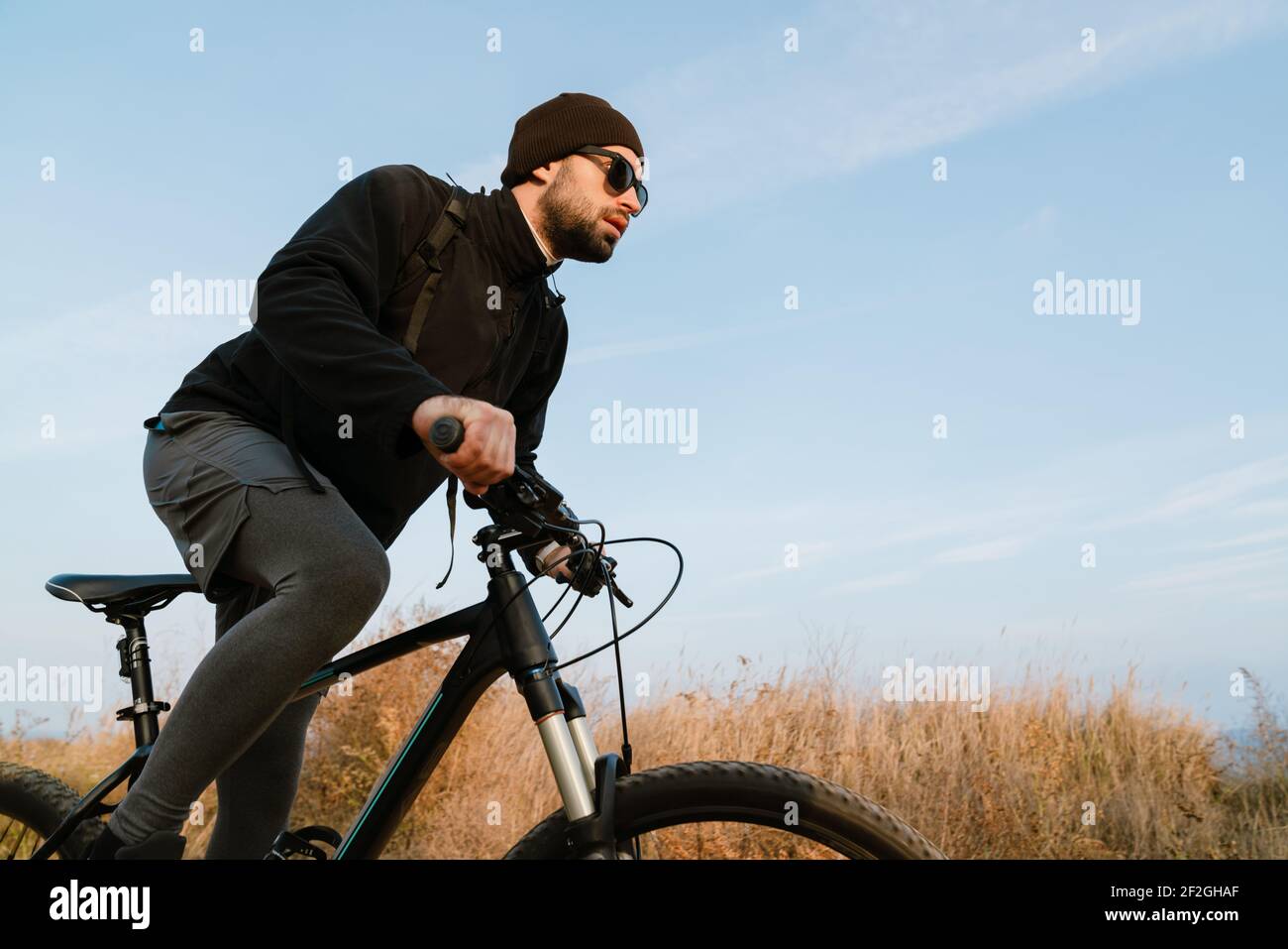 Handsome unshaven guy in sunglasses riding his bicycle outdoors Stock ...