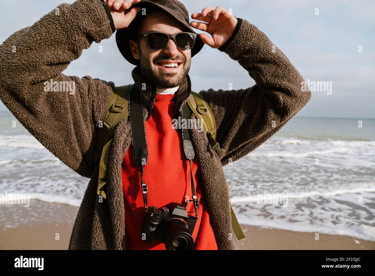 Happy handsome photographer in sunglasses walking with digital camera ...