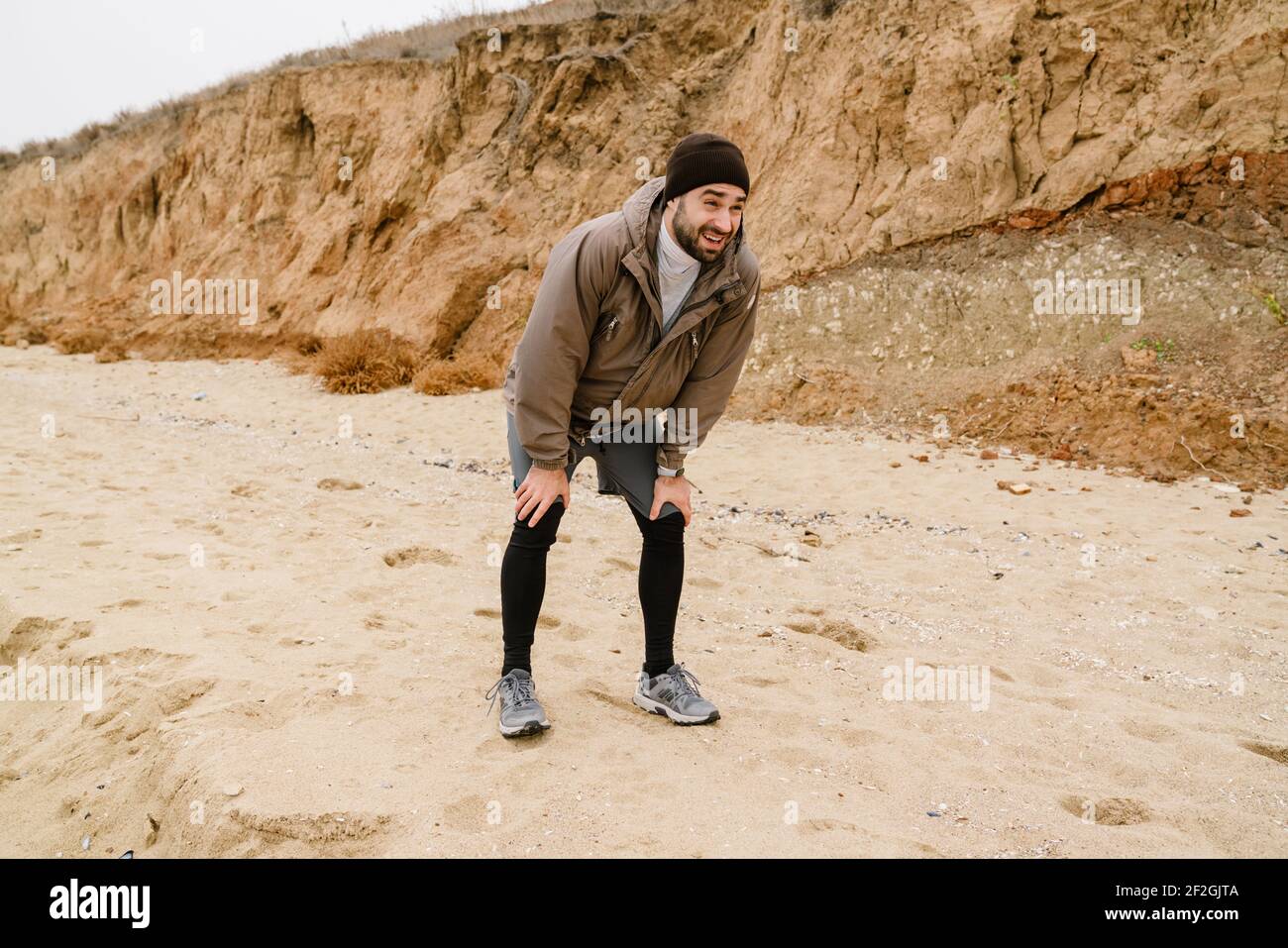 Young tired sportsman resting while working out on beach Stock Photo ...